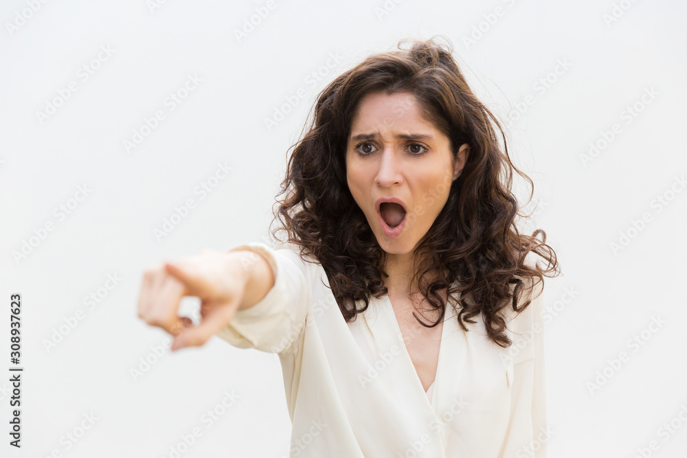 Shocked exaggerated woman with open mouth pointing finger away. Wavy ...