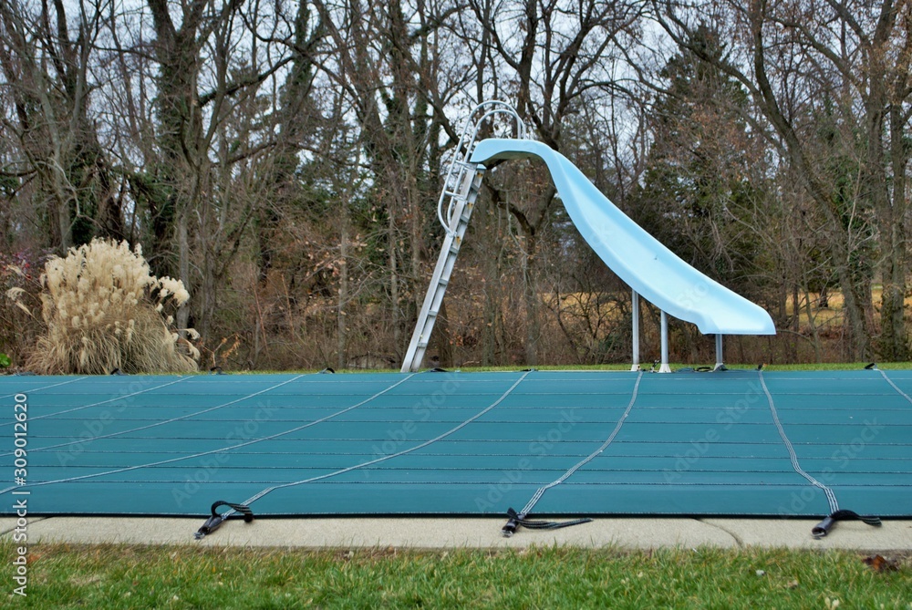 backyard swimming pool with diving board and pool slide tarped up and ...