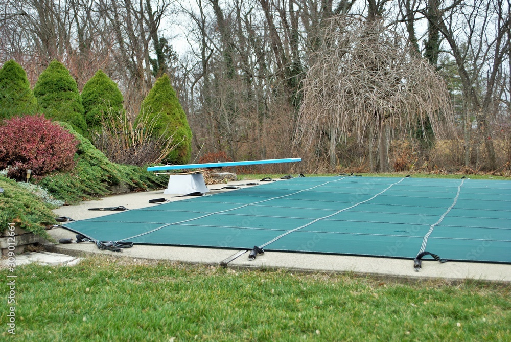 backyard swimming pool with diving board and pool slide tarped up and ...