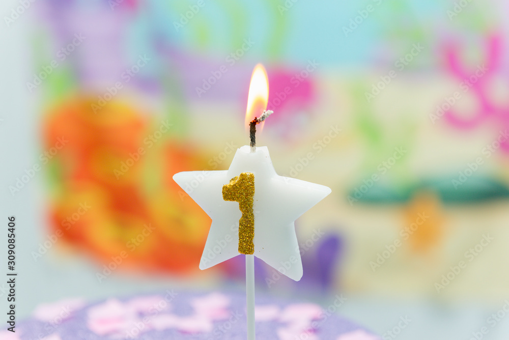 Lighted birthday candle in star shape with blurred background. 1 year ...