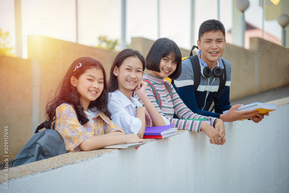 Four asian teenager students standing in school and smiling at camera ...