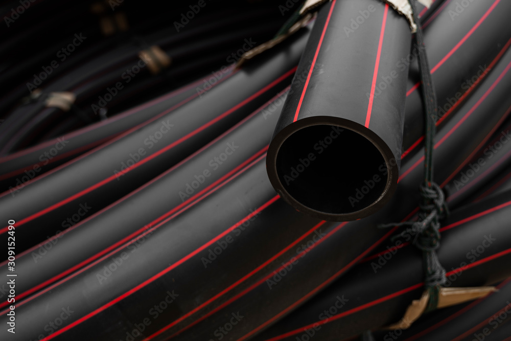 Black rubber or plastic pipes with a red lines as a construction ...