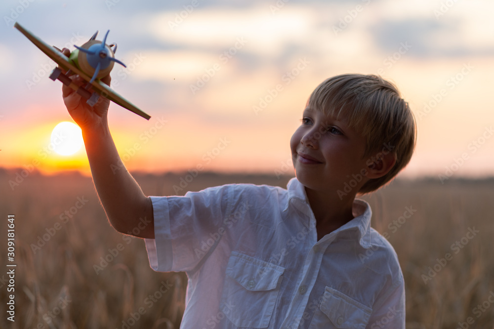 Happy child playing with a toy plane in nature during summer sunset ...