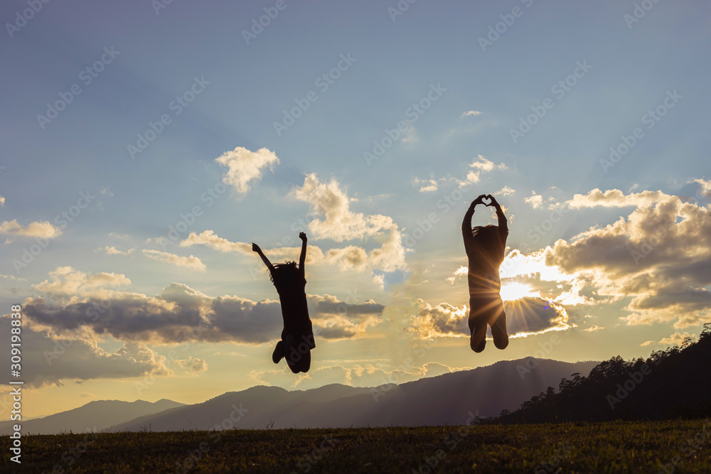 Silhouette of happy children jumping playing on mountain at sunset time ...