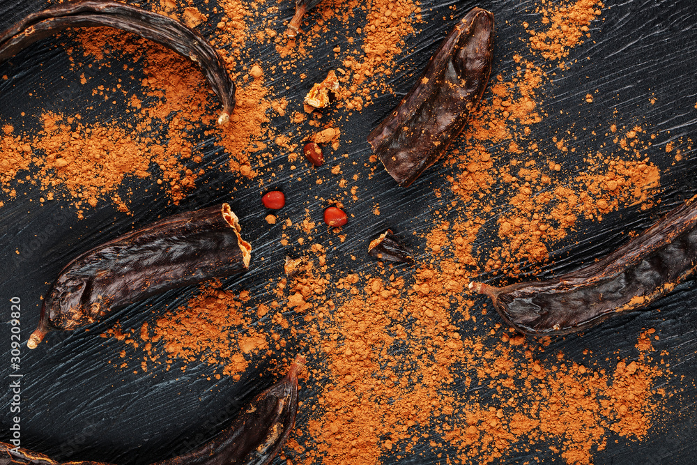 Carob carob fruit with powder on black background. Blast the Sweet ...