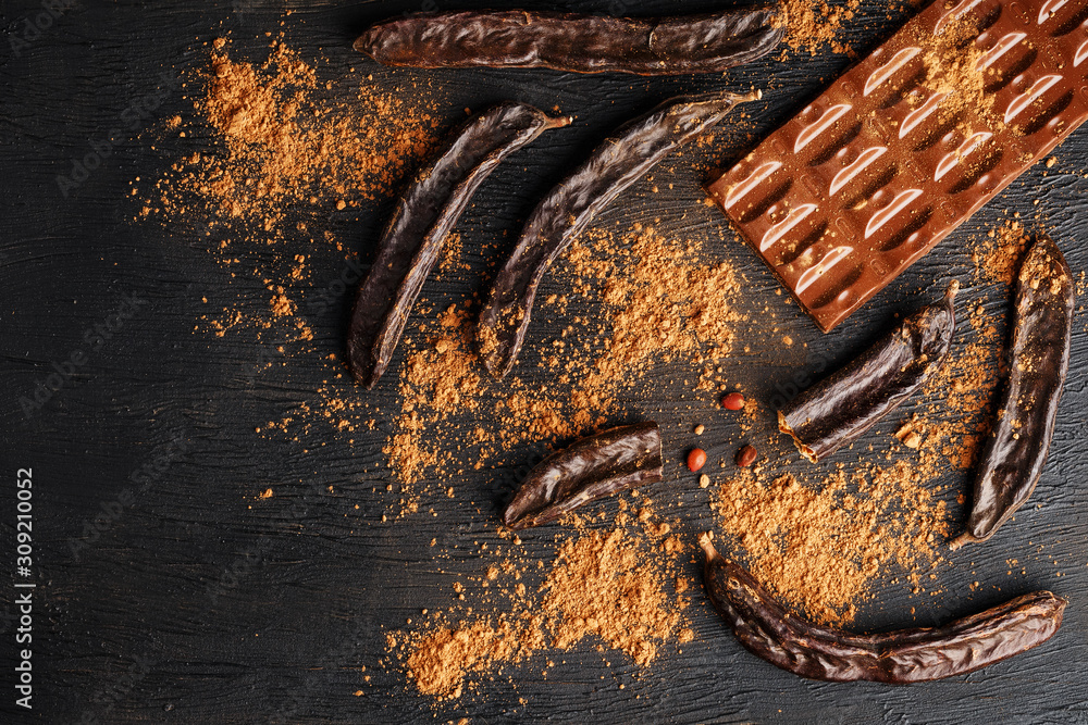 The pods of the carob chocolate bar on a black background. Sweets ...