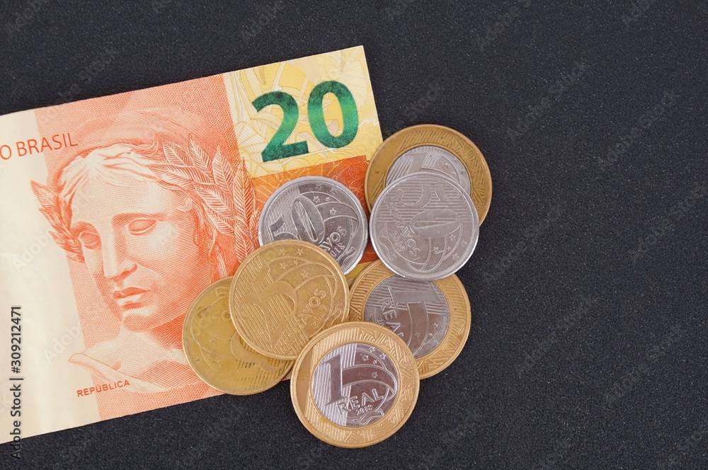 Brazilian 20 reais banknote and coins on black background. Brazilian ...