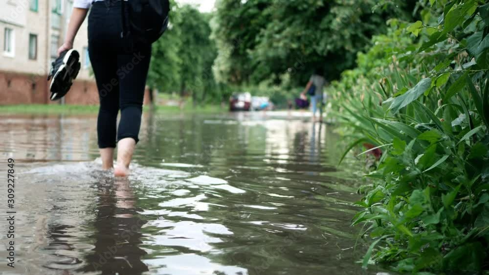 Wet people, girl barefoot in dirty water on the flooded city street ...