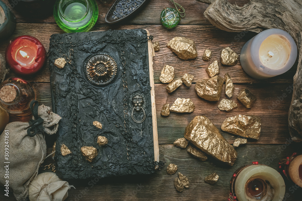 Golden stones and ancient magic book on alchemist table concept ...