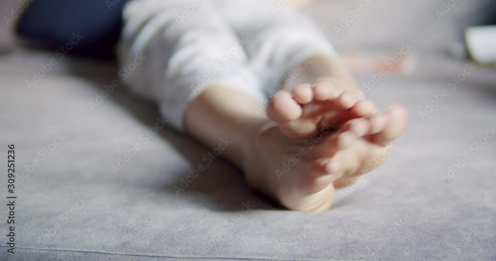 Asian woman scratching on her feet while sitting on a sofa at home ...