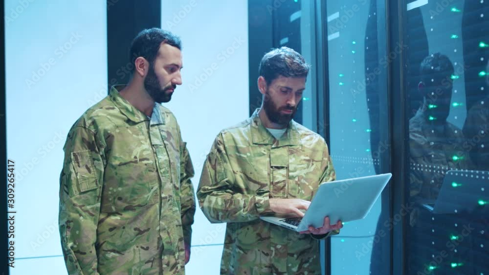 Two military men running diagnostics on laptop at cyber space. Soldiers ...