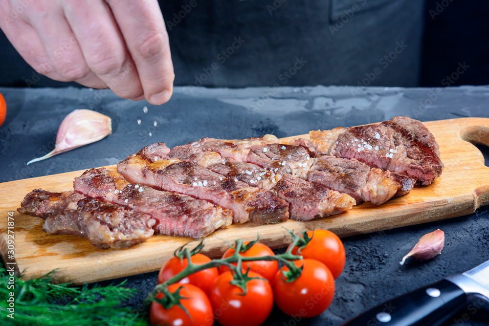 Marbled beef steak. The man is salting the medium-rare meat. Freshly ...