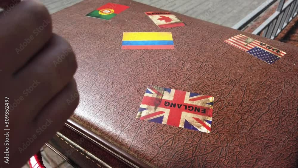 A man sticks stickers with flags of various countries on an old vintage ...