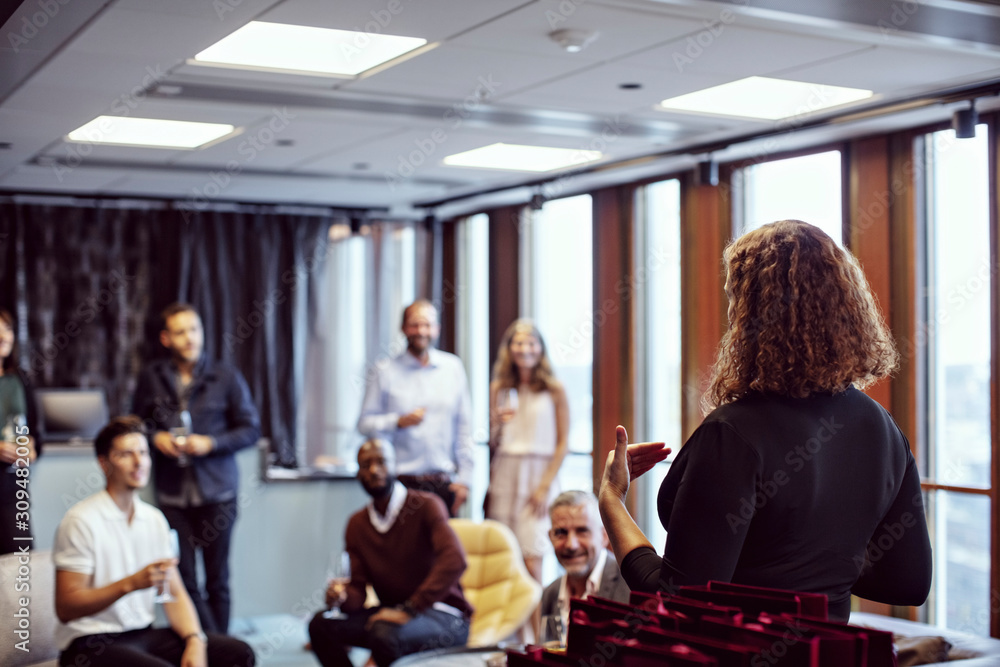 Businesswoman giving speech to coworkers during office party after work ...