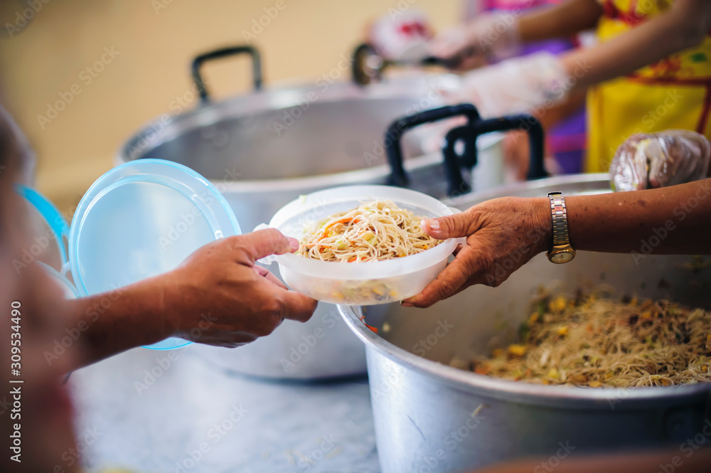 The hands of the poor receive food that volunteers share to alleviate ...