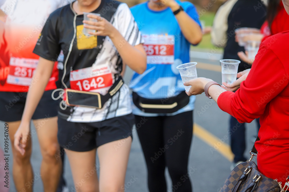 Hand of a volunteer giving a cup of water at a refreshment point in a ...