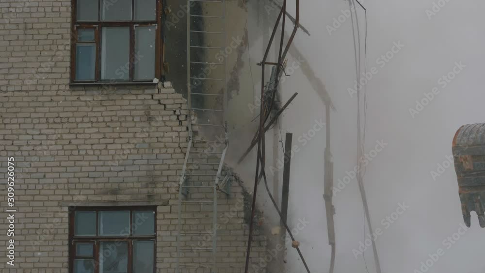 Hydraulic arm of the excavator smashes brick wall and the wall is ...