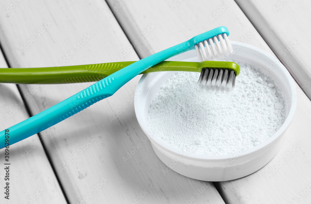 Two toothbrushes, tooth powder on white wooden background. Minimalism ...