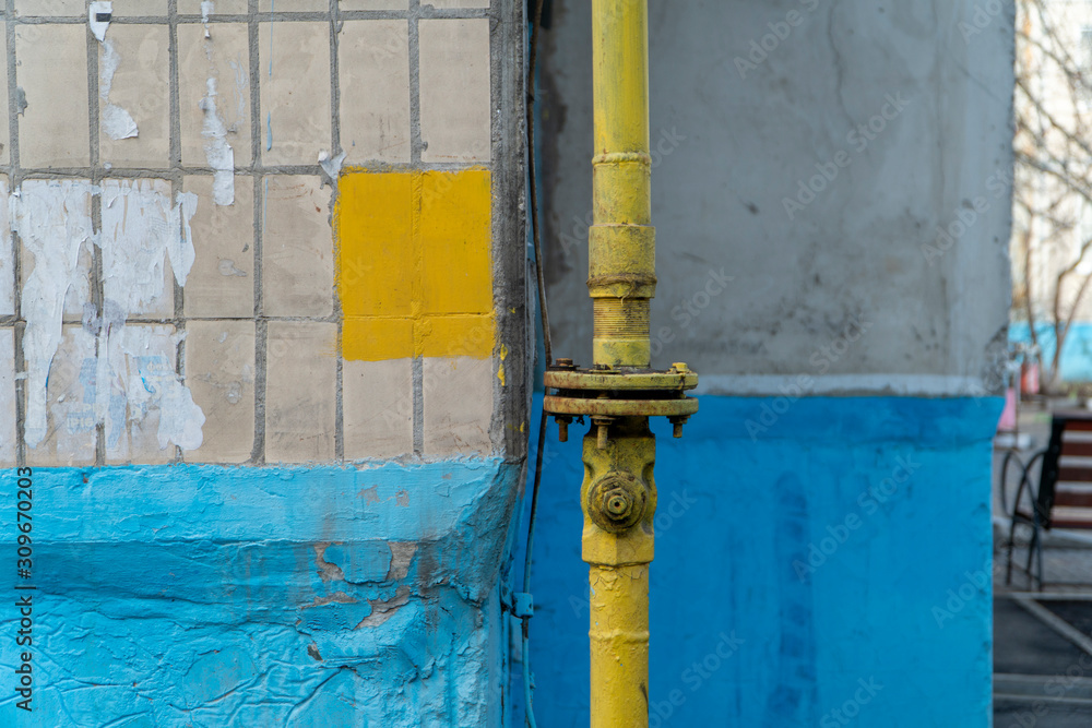 Yellow gas valve with flanges on the pipe near corner of the house. Gas ...