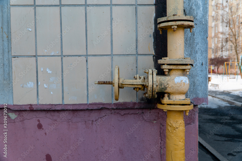 Yellow gas valve on the vertical pipe near wall with tiles and corner ...