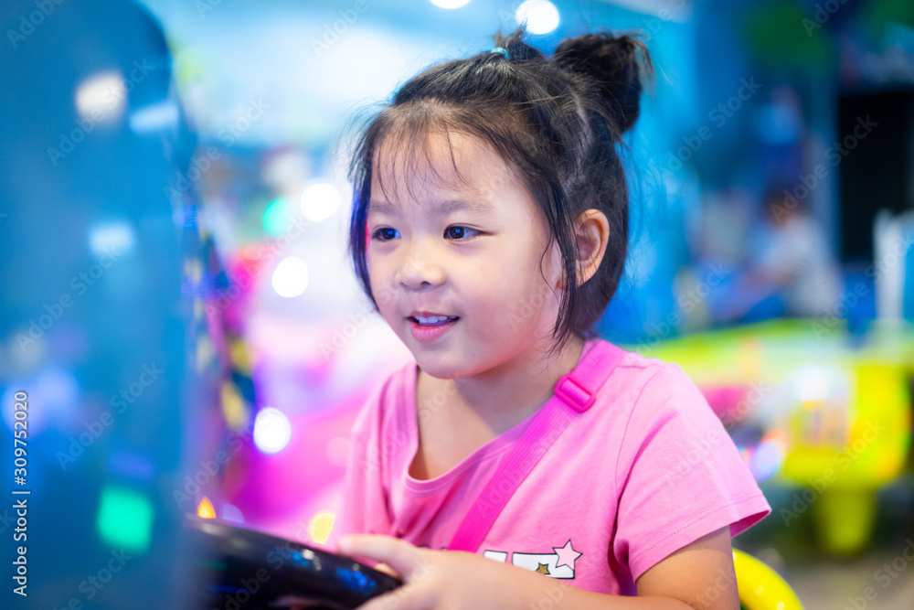 Foto de Little asian girl playing Racing car arcade game machine in ...