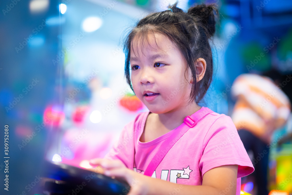 Little asian girl playing Racing car arcade game machine in Game center ...