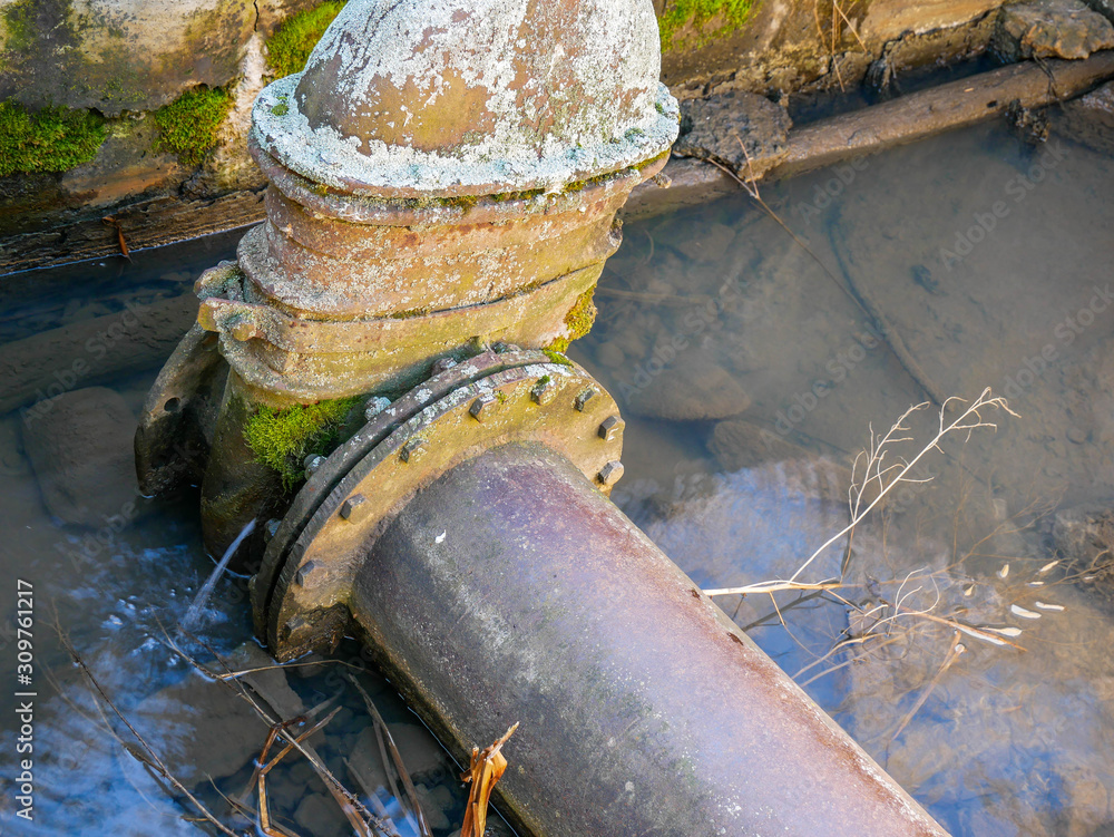 Leaking industrial pipe transporting the sewage water in a concrete pit ...
