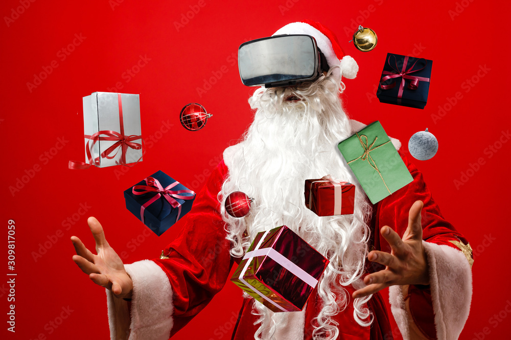 Santa Claus wearing virtual reality goggles, on a red background ...