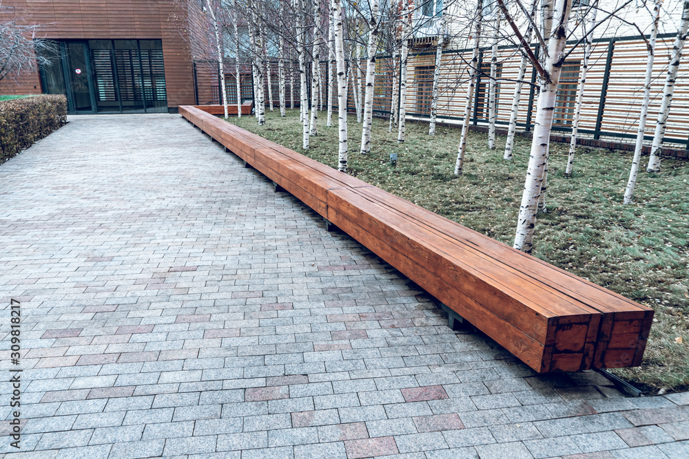 Modern long wooden bench in the park. Design of urban public space. The ...