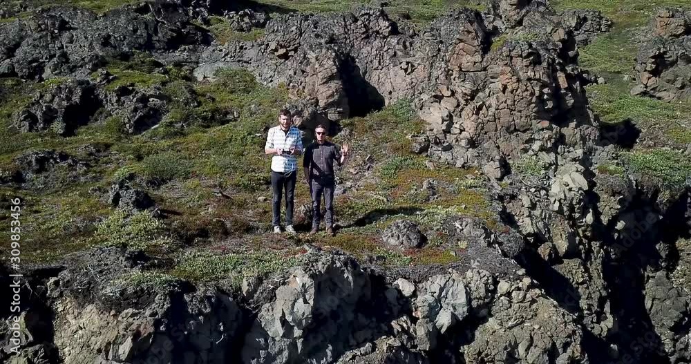 Aerial shot of drone pulling back from Arctic Island with two tourist ...