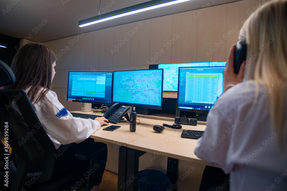 Female security guards working on computers while sitting in the main ...