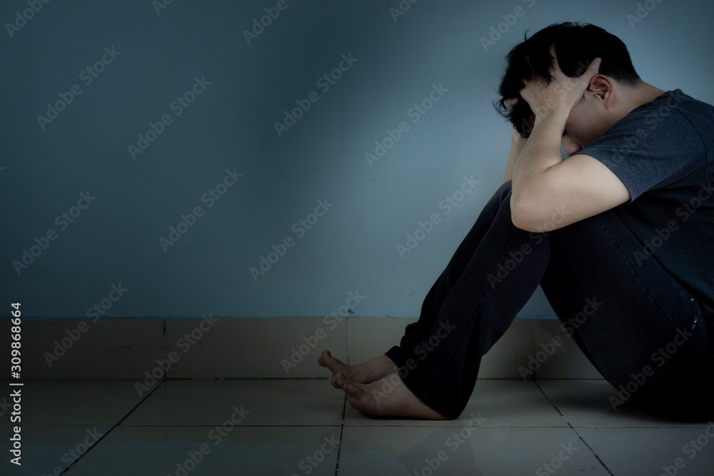 sad man hug his knee and cry sitting alone in a dark room. Depression ...