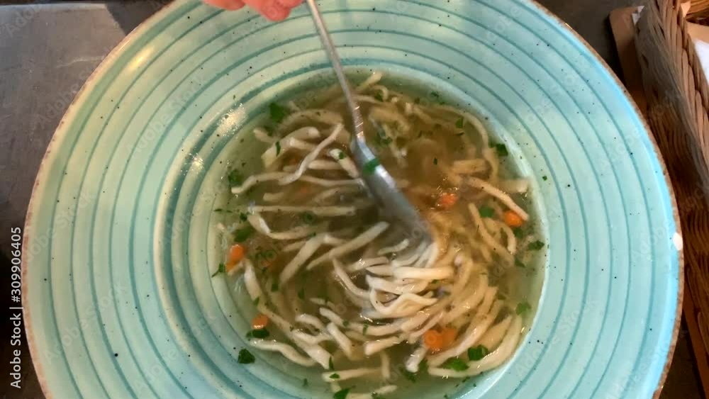 Traditional Polish chicken soup with noodles and parsley. Mixing the ...