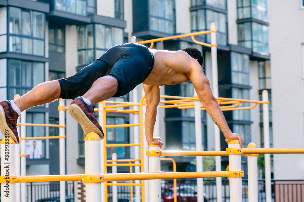 Portrait of athlete young mixed race man doing exercises on horizontal ...