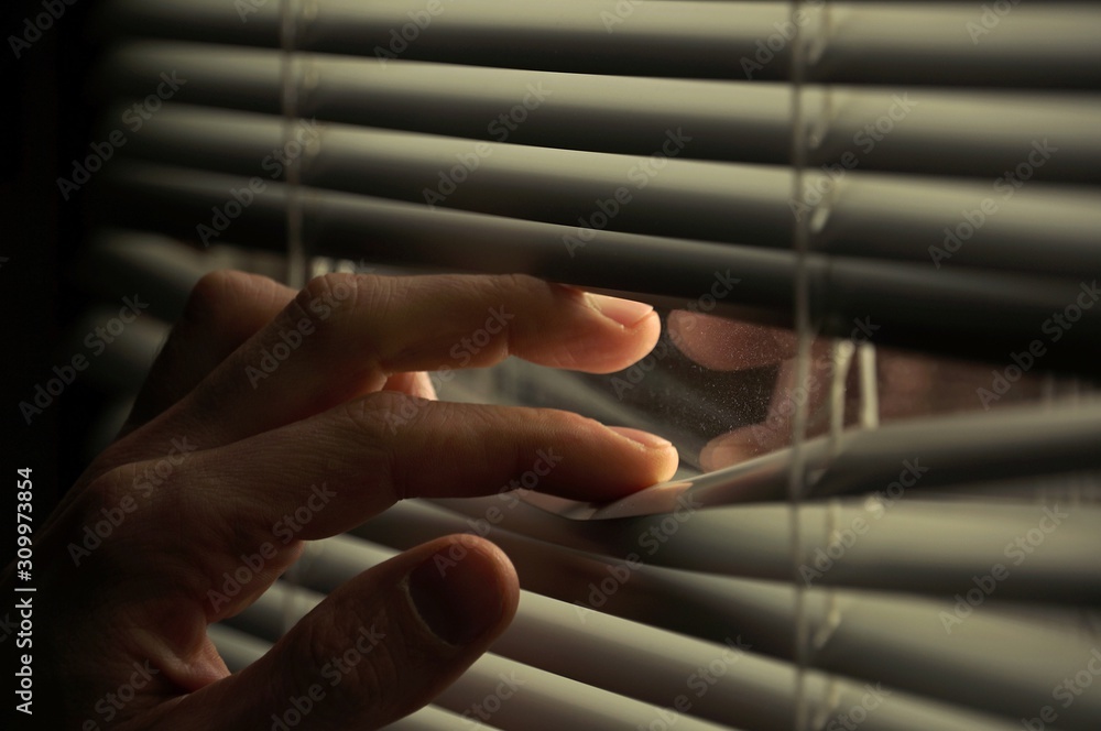 Caucasian hand opening window blind to look outside. Peeping through ...