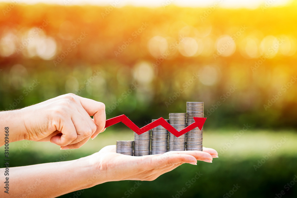 Woman hand hold a stacking coins with growing and red arrow graph with ...