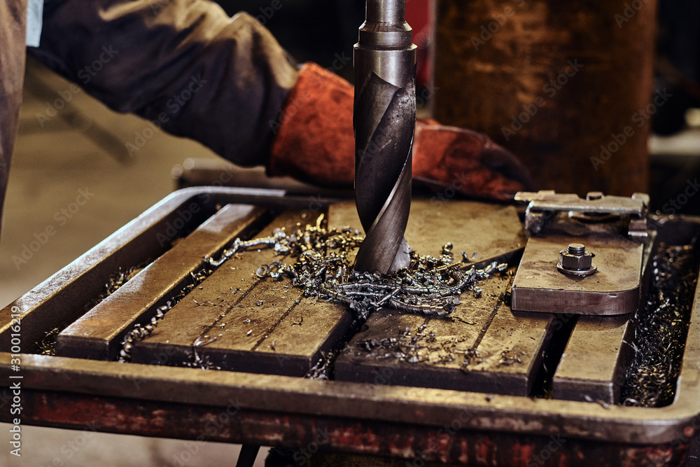 Drilling hole in the metal with giant drill at steel factory by worker ...
