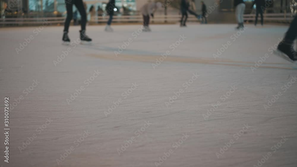 Legs of unrecognizable people ride on a city open ice rink in the ...