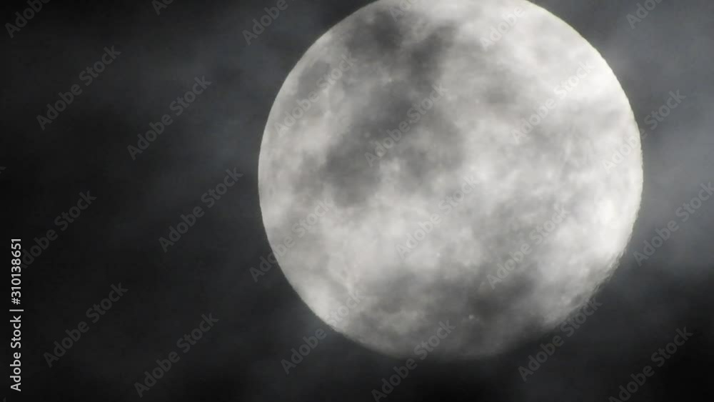 Haunted full moon with eerie dark clouds moving past in the foreground ...