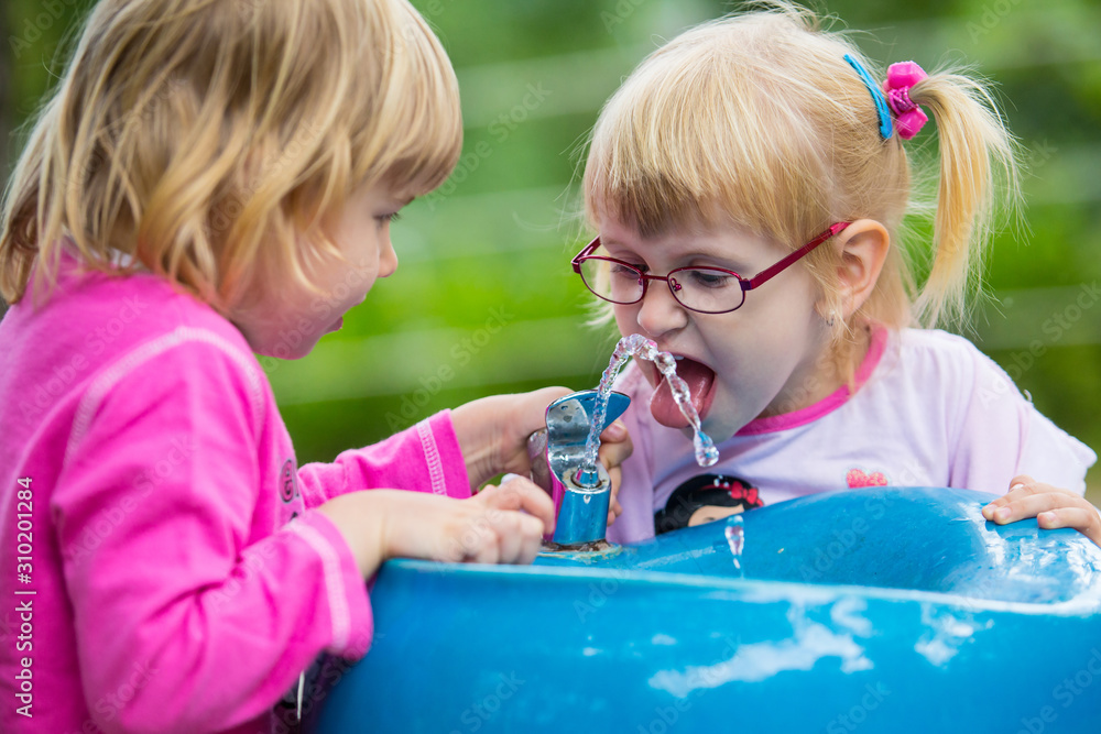 Young children drink water from public fountain Stock Photo | Adobe Stock