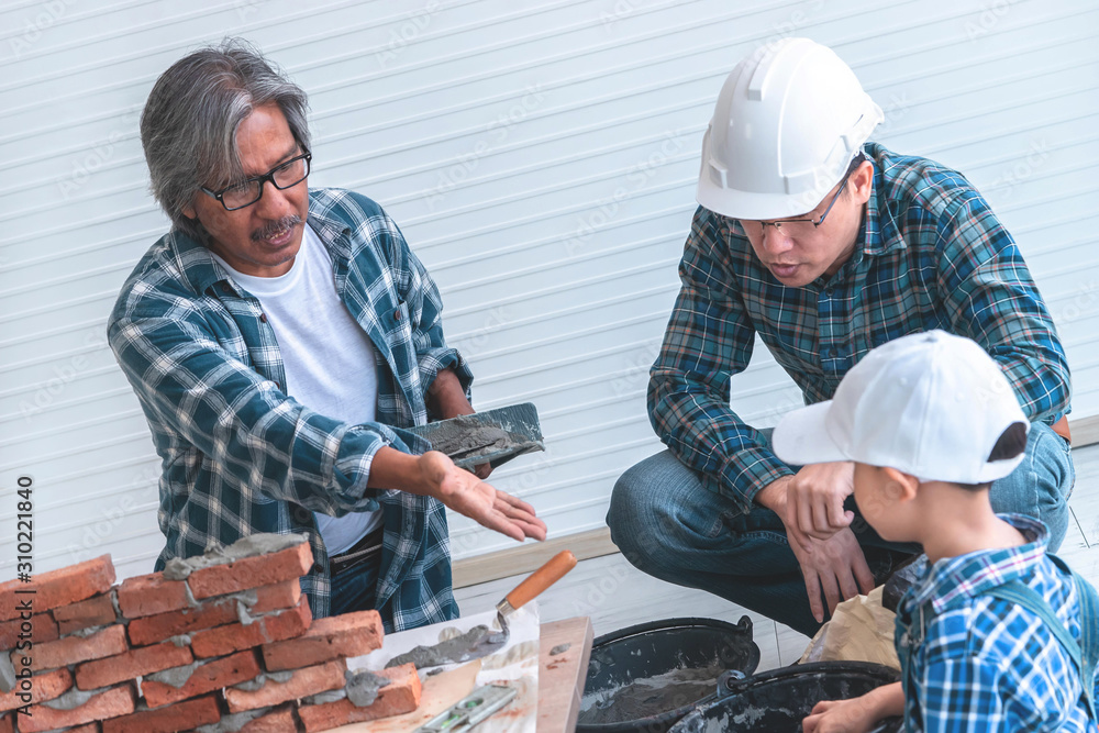 Little boy is learning how to build brick wall from his construction ...