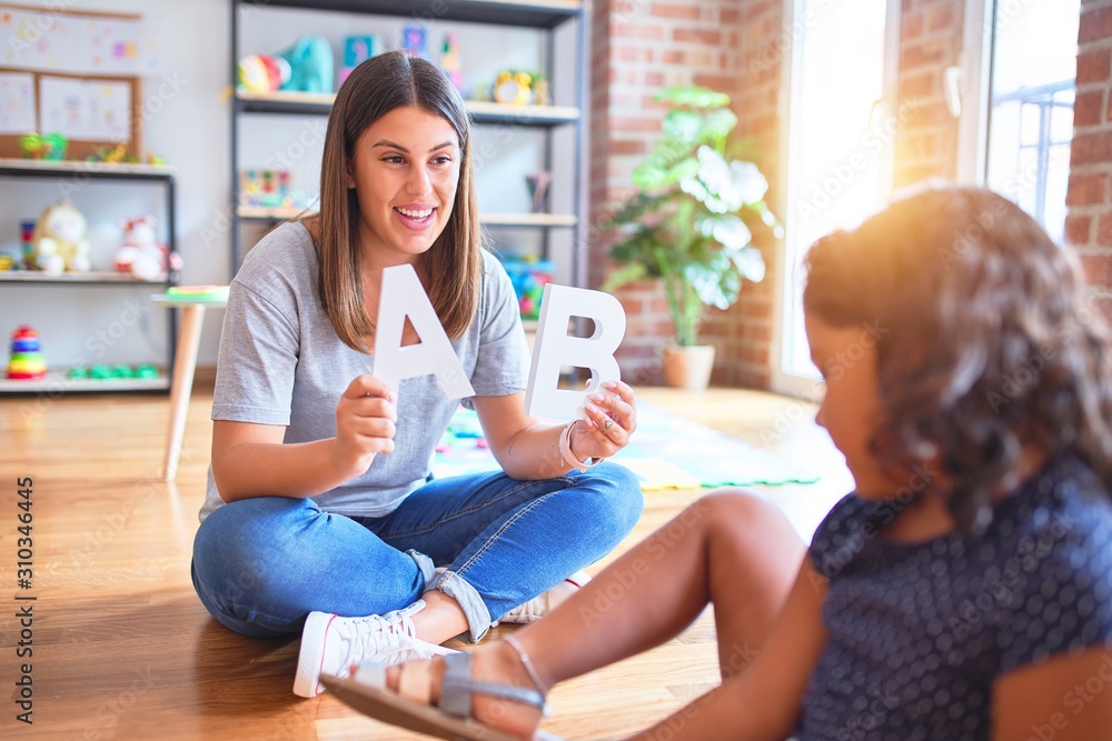 Beautiful teacher teaching alphabet to student toddler girl at ...
