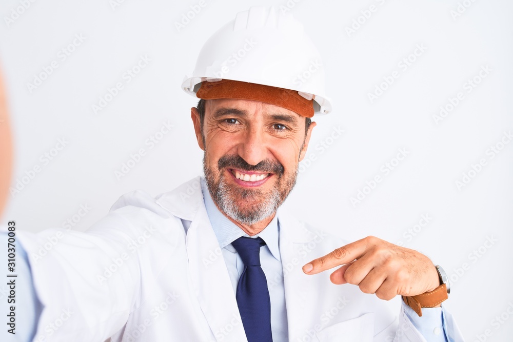 Middle age engineer man wearing helmet make selfie over isolated white ...