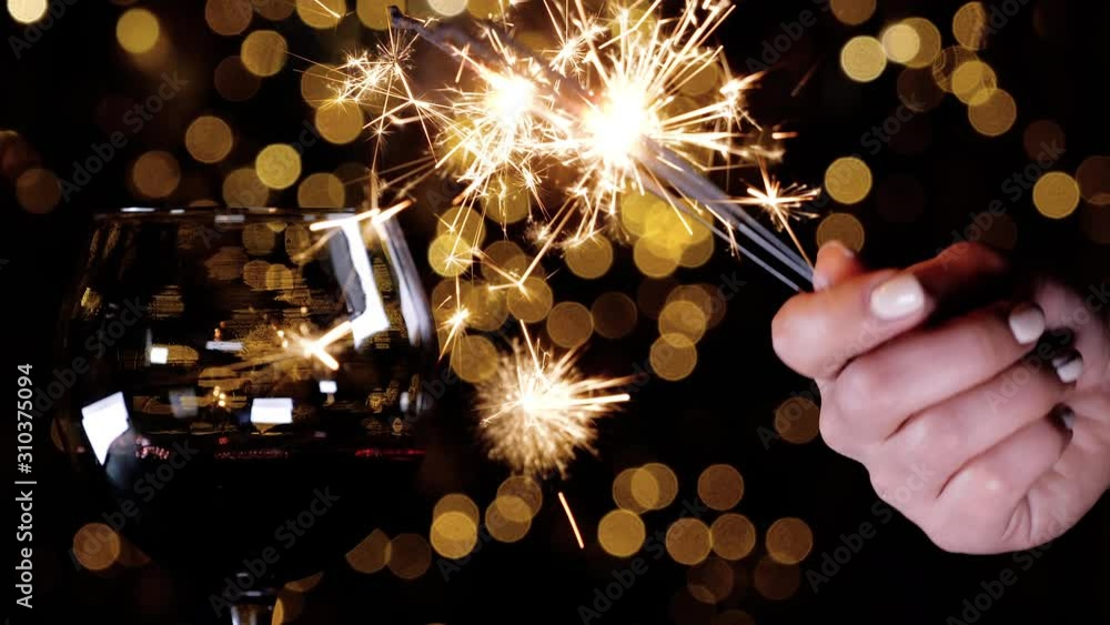 Sparkler flashes in hands on a black background close-up. The bright ...