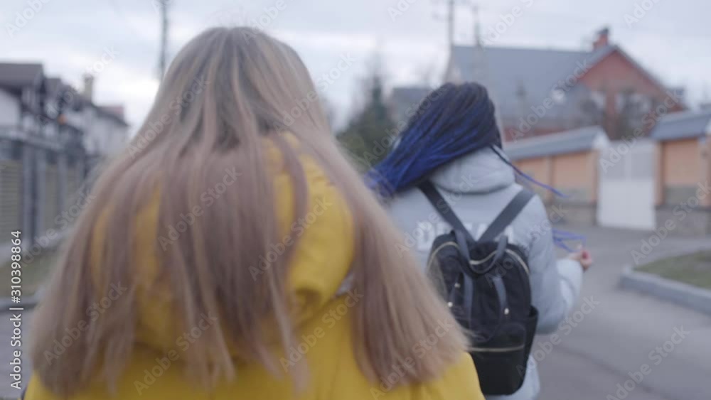 Two female friends talking, turning back to each other, African ...