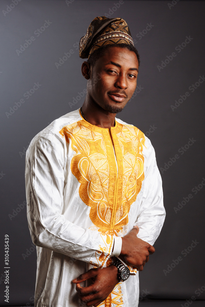 Young man in yoruba and white and gold national clothes standing and ...