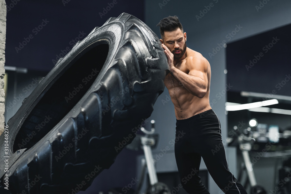 Shirtless muscular guy flipping huge tire at gym Stock Photo | Adobe Stock
