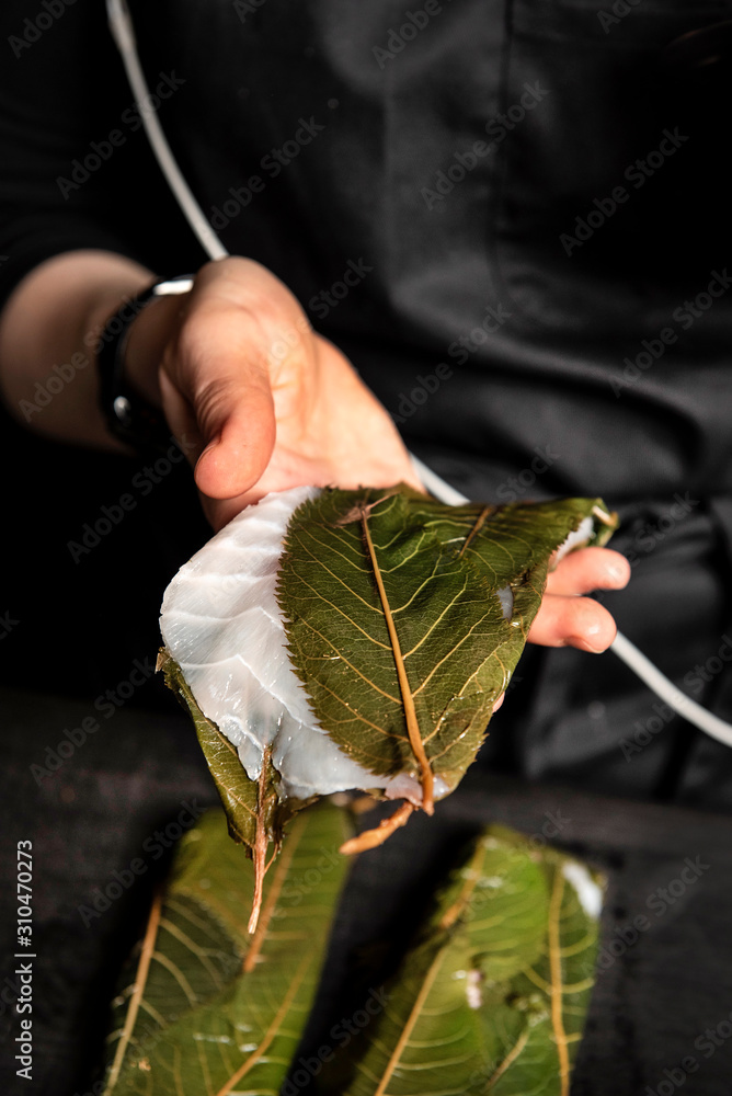 Chef wrapping Japanese Knifejaw fish with cherry blossom leaves Stock ...