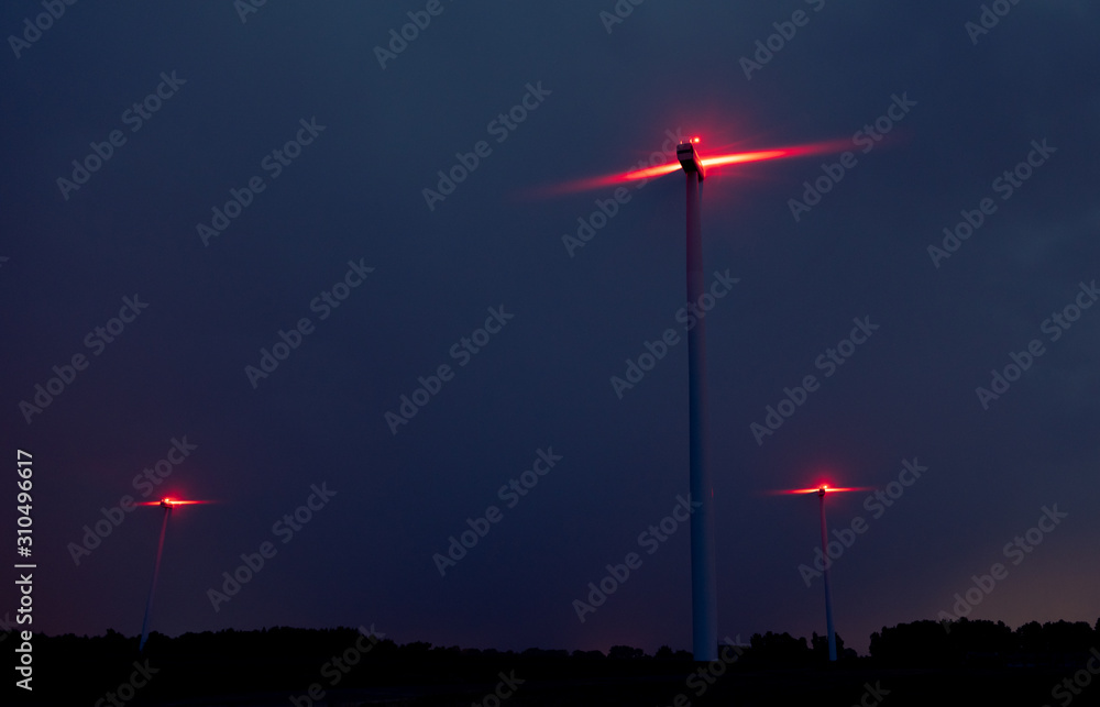 Wind turbines on a dramatic dark blue clouds in the sky. Storm ahead is ...