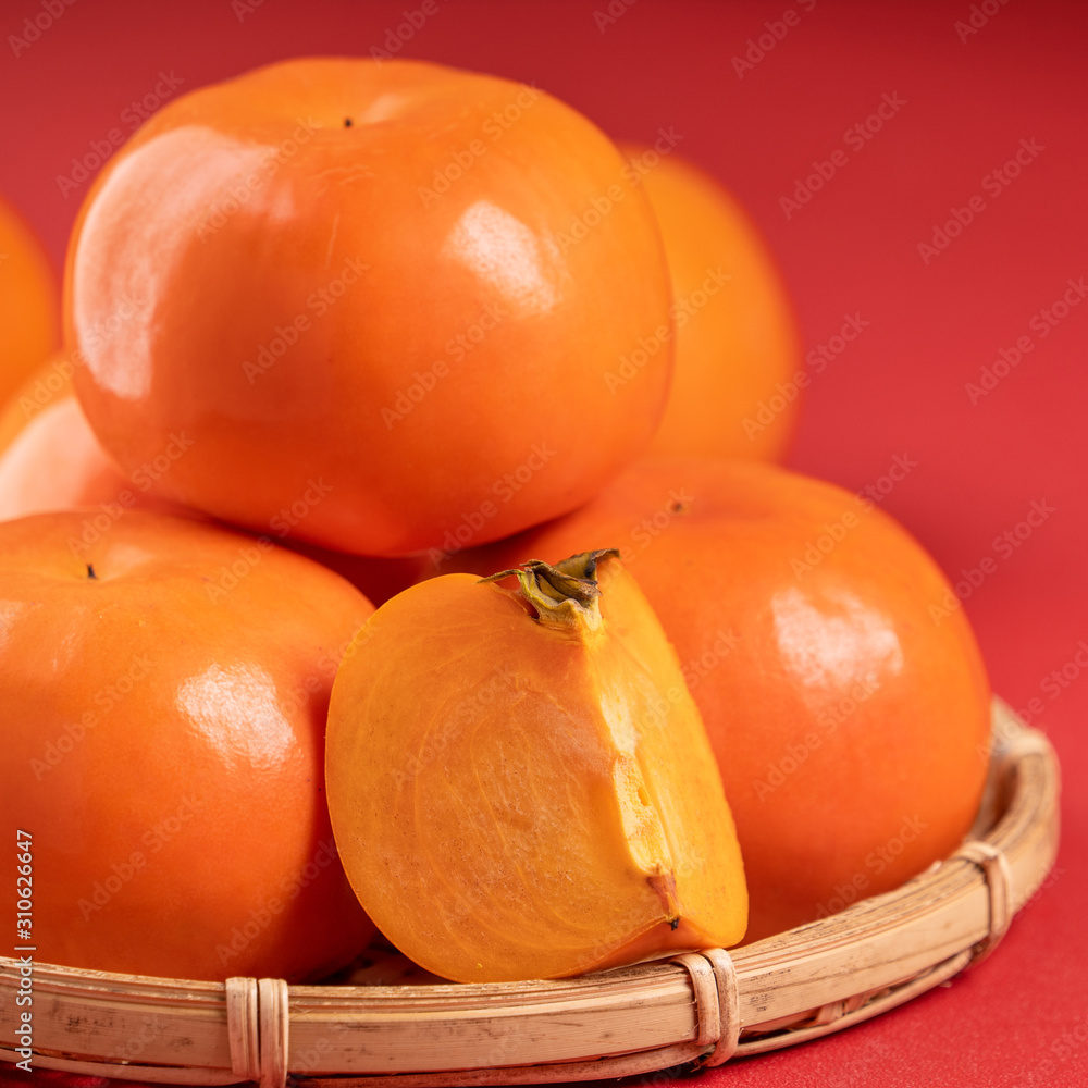 Fresh beautiful sliced sweet persimmon kaki isolated on red table ...